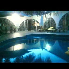 Piscina com espreguiçadeiras e área de estar coberta.