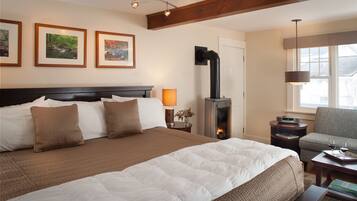 Quarto de hotel com uma cama grande, lareira, sofá e quadros nas paredes.
