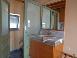 Casa de banho com lavatório, espelho e sanita.