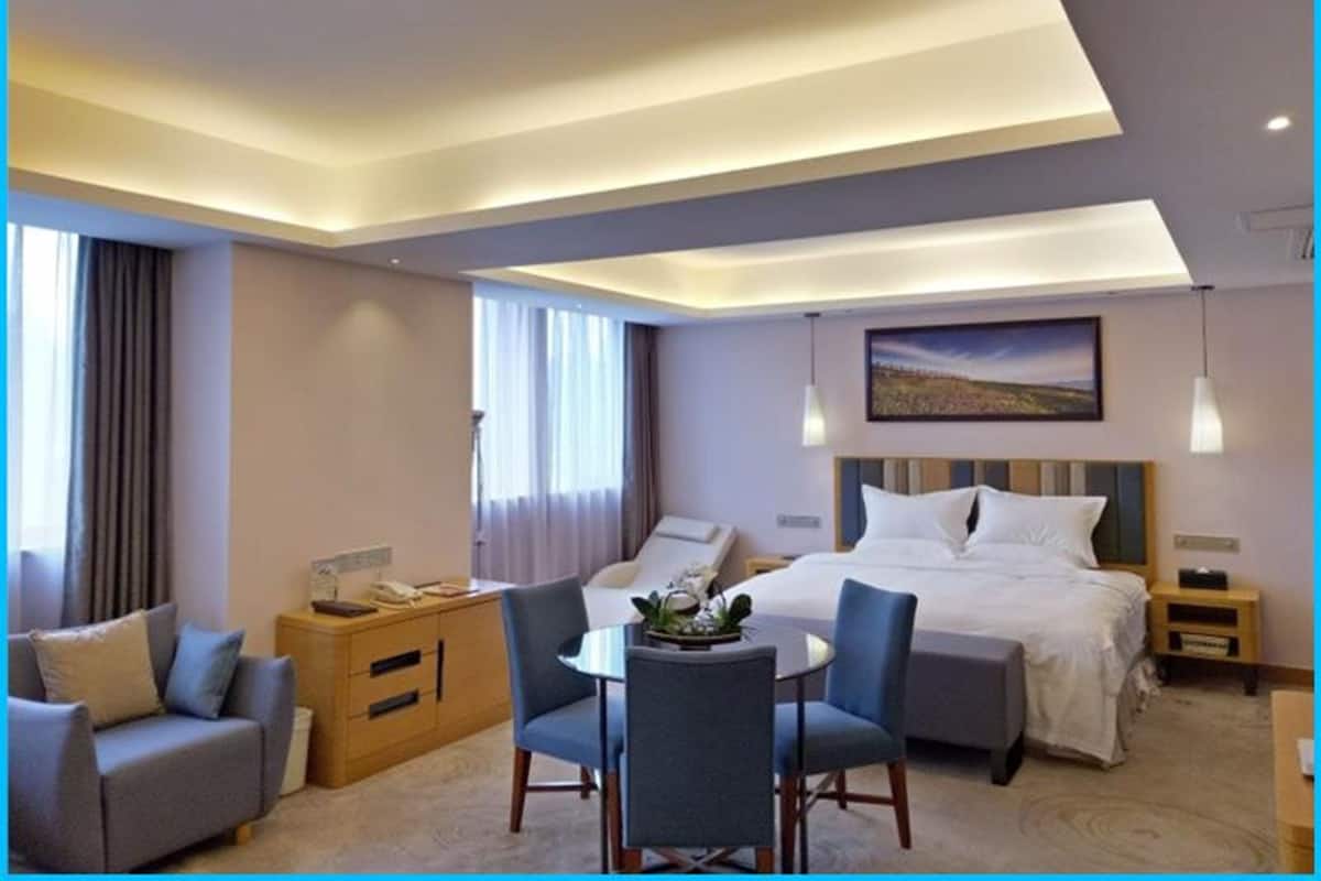 Quarto de hotel moderno com uma cama grande, uma escrivaninha, um sofá e uma mesa de jantar.