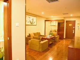 Um saguão de hotel com um conjunto de sofás, uma mesa de centro e piso de madeira.