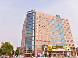 Hotel de vários andares com fachada moderna, combinando vidro e tijolos.