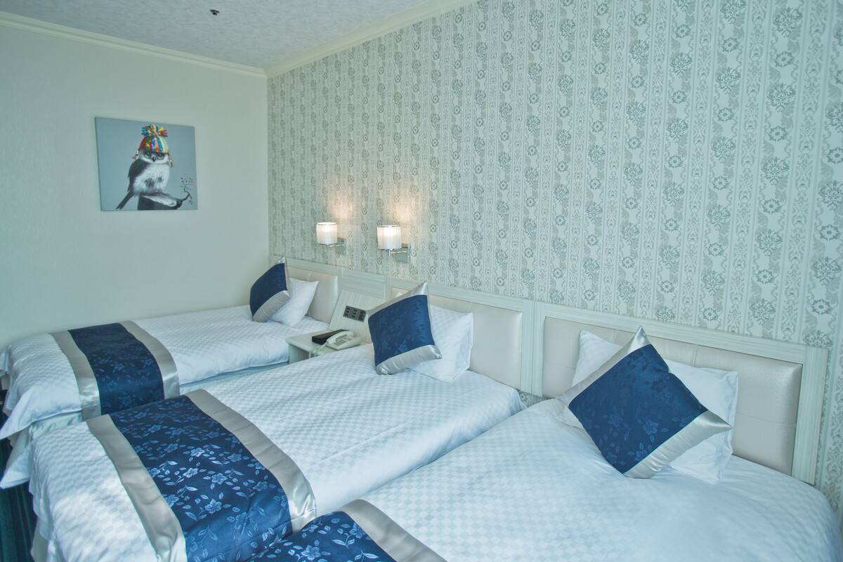 Quarto de hotel com duas camas, uma mesa de cabeceira e um quadro na parede.