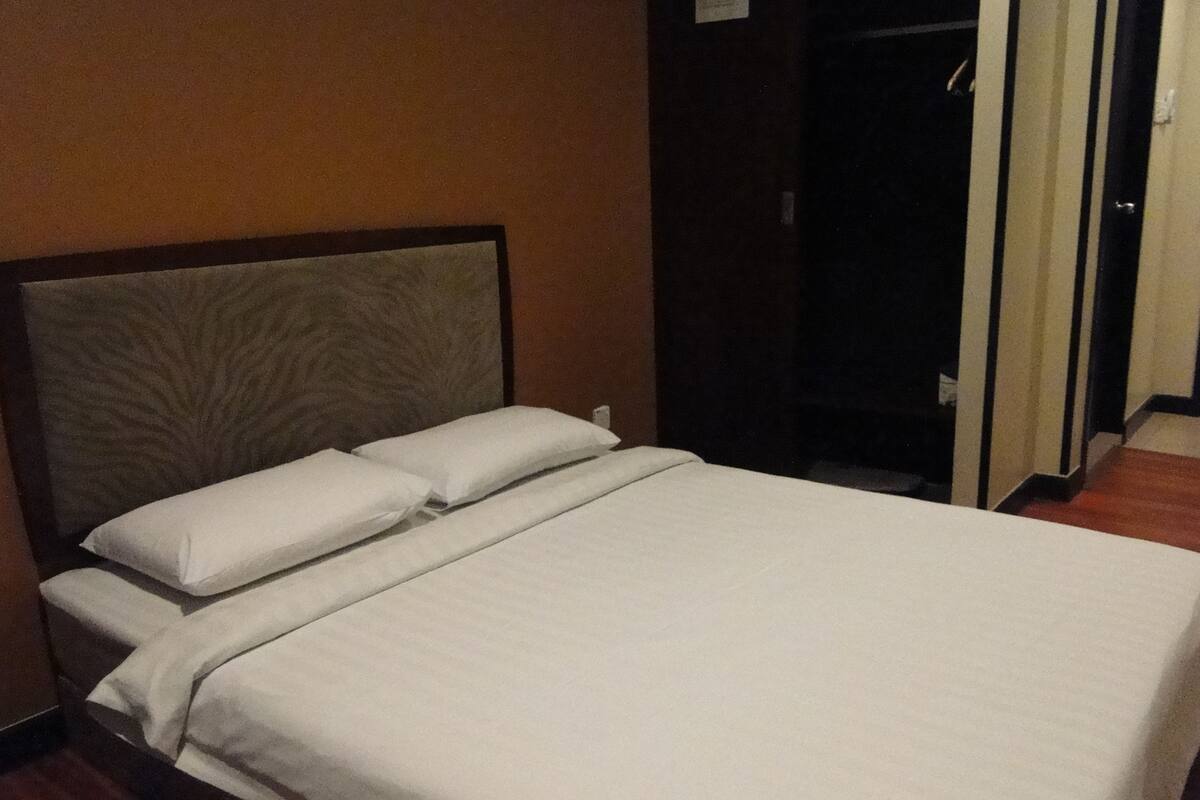 Quarto de hotel com uma cama, um guarda-roupa e um espelho.