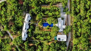 Vista aérea de uma propriedade residencial com várias casas, uma piscina e vegetação ao redor.