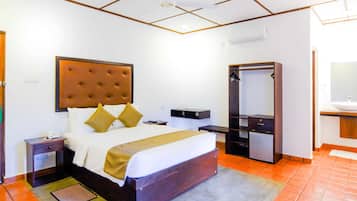 Quarto de hotel com uma cama grande, mesa de cabeceira com telefone, armário e banheiro com pia e espelho.