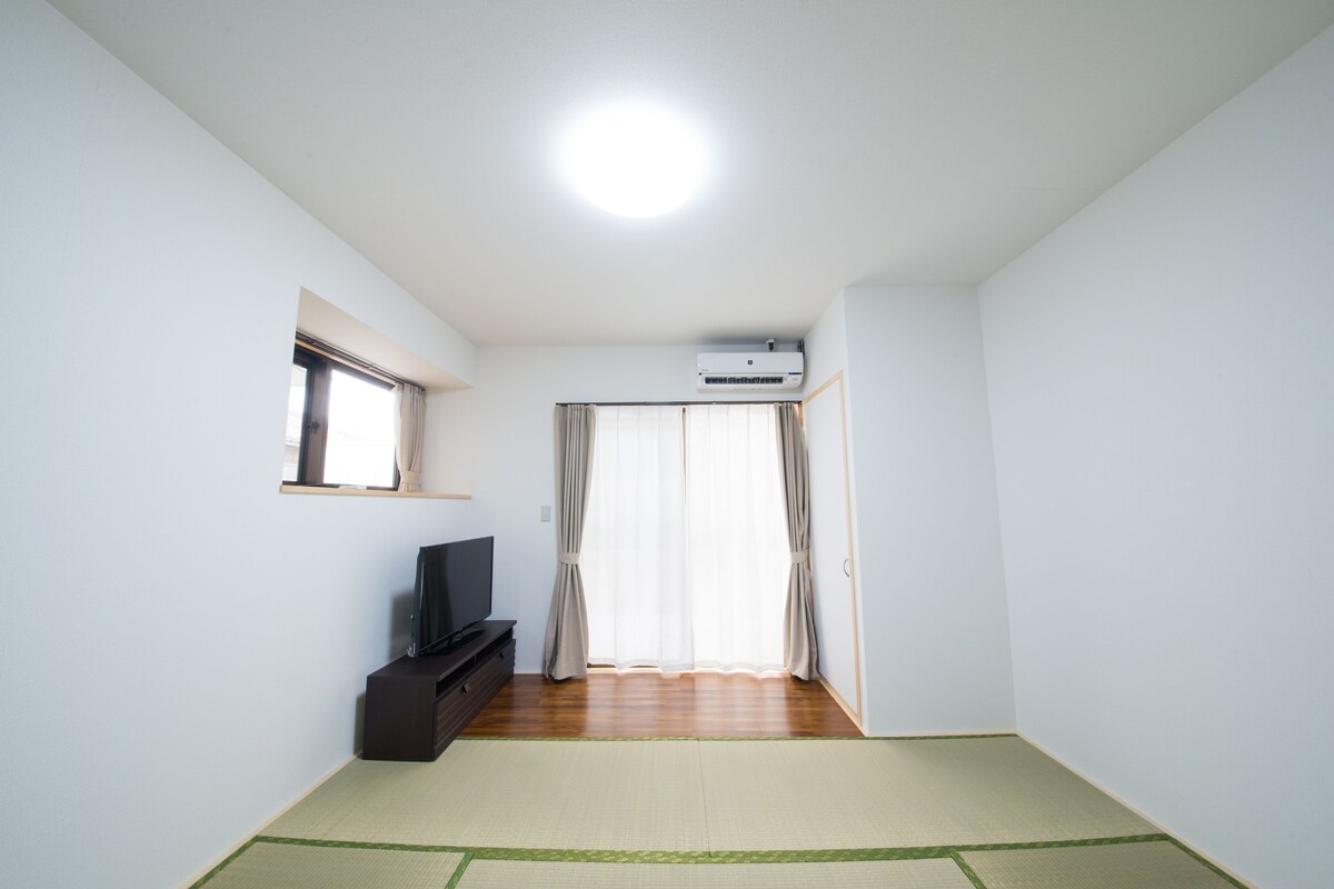 Quarto com televisão em móvel, janela e aparelho de ar condicionado.