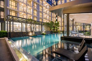 Um hotel moderno com uma grande piscina interior, vários andares e fachada bem iluminada.