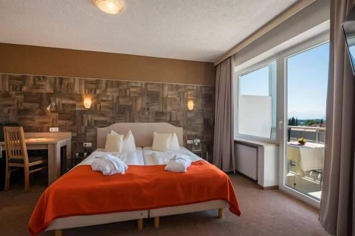 Quarto de hotel com uma cama grande, uma escrivaninha e vista para o exterior.