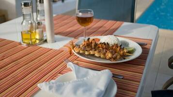 Uma mesa de jantar com um prato de camarão grelhado, um copo de cerveja e acompanhamentos.