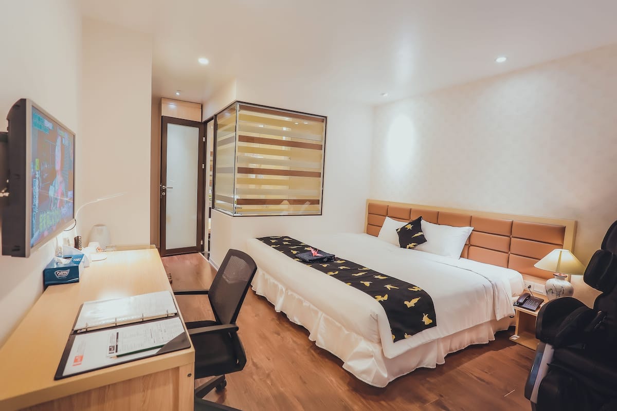 Quarto de hotel com cama, escrivaninha, cadeira e poltrona de massagem.