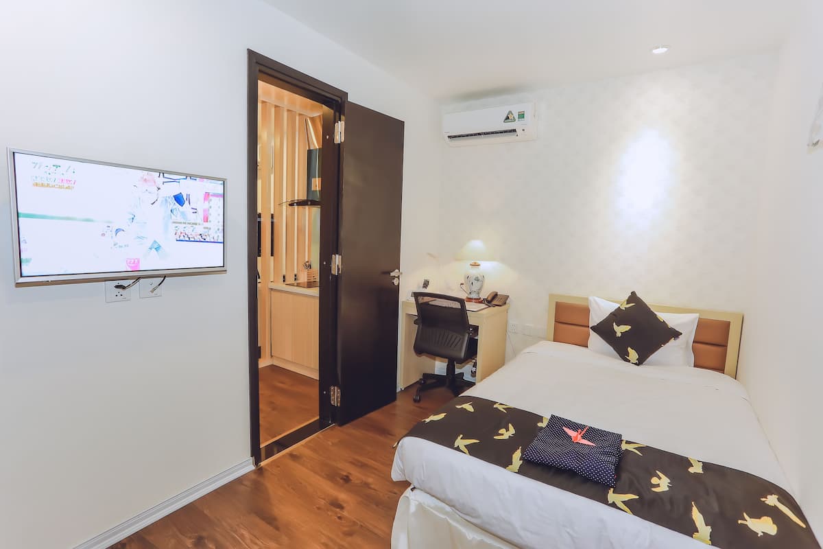 Quarto de hotel com cama, escrivaninha, ar condicionado e televisão mostrando um mapa.