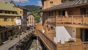 Um edifício de madeira tradicional com varandas, um caminho de pedra e montanhas ao fundo.