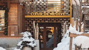 Fachada de hotel com design de treliça de madeira e placa com a inscrição "COEUR DE MEGEVE".