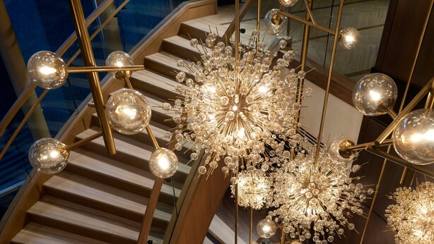 Interior moderno com escada de madeira e várias luminárias pendentes.