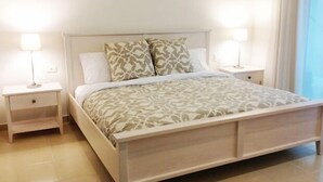 Um quarto com uma cama de madeira, duas mesas de cabeceira e um criado-mudo.