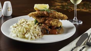 Prato de peixe frito com limão e endro, acompanhado de salada de repolho e legumes.