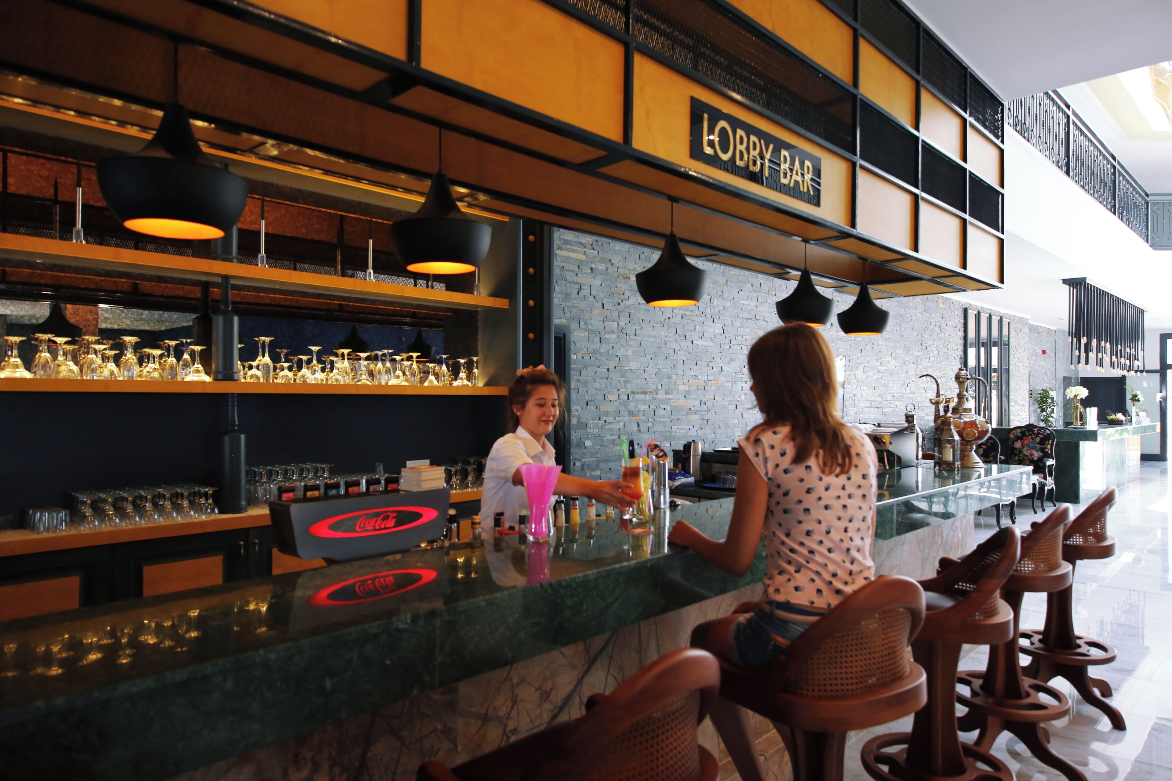 Uma área de bar com balcão, banquetas e um bartender.