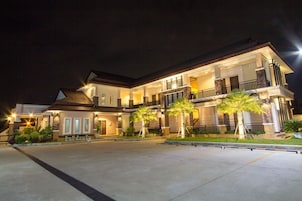 Um hotel com vários andares, entrada coberta, área de estar ao ar livre e estacionamento.