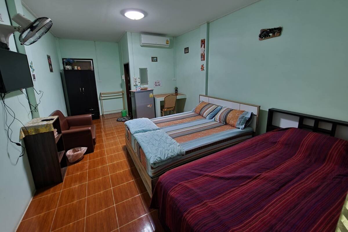 Quarto com duas camas, uma escrivaninha, uma cadeira, uma televisão e ar condicionado.