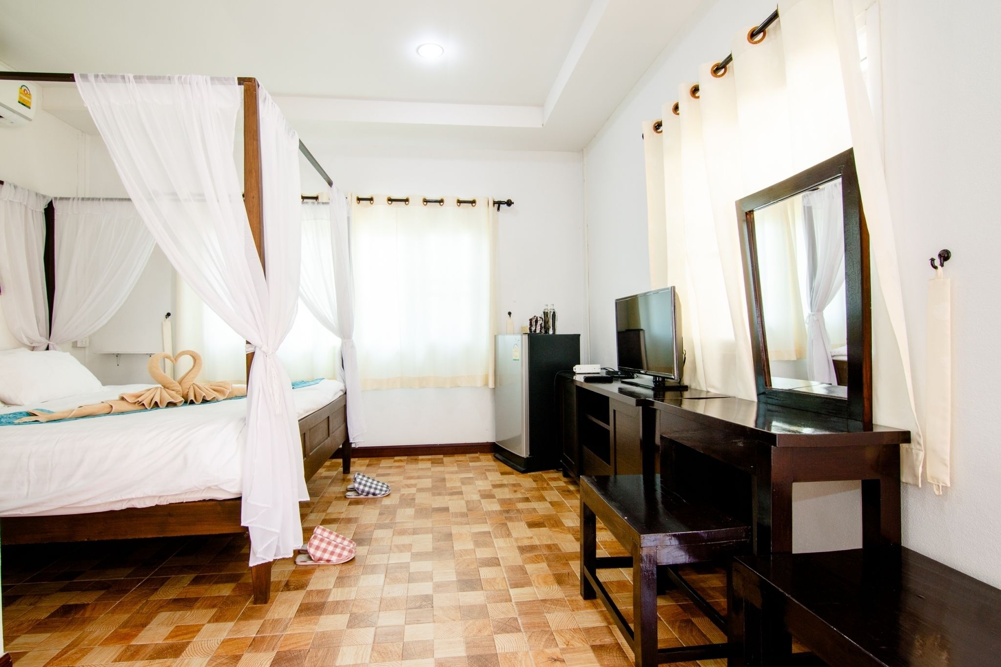 Quarto com cama de dossel, televisão e escrivaninha com cadeira.