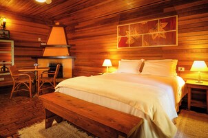 Um quarto de madeira acolhedor com uma cama, duas cadeiras, uma mesa e uma lareira.