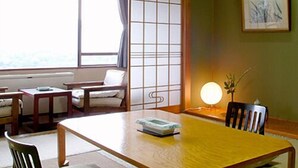 Um quarto em estilo japonês tradicional, com tatames, uma mesa baixa e um sofá.