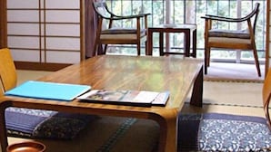 Um quarto tradicional em estilo japonês, com esteiras de tatame, uma mesa baixa e portas deslizantes.