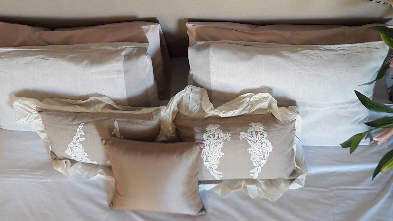 Uma cama com quatro almofadas, duas delas com bordado floral.