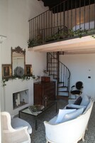 Uma sala de estar espaçosa com teto alto, escada e varanda com plantas.