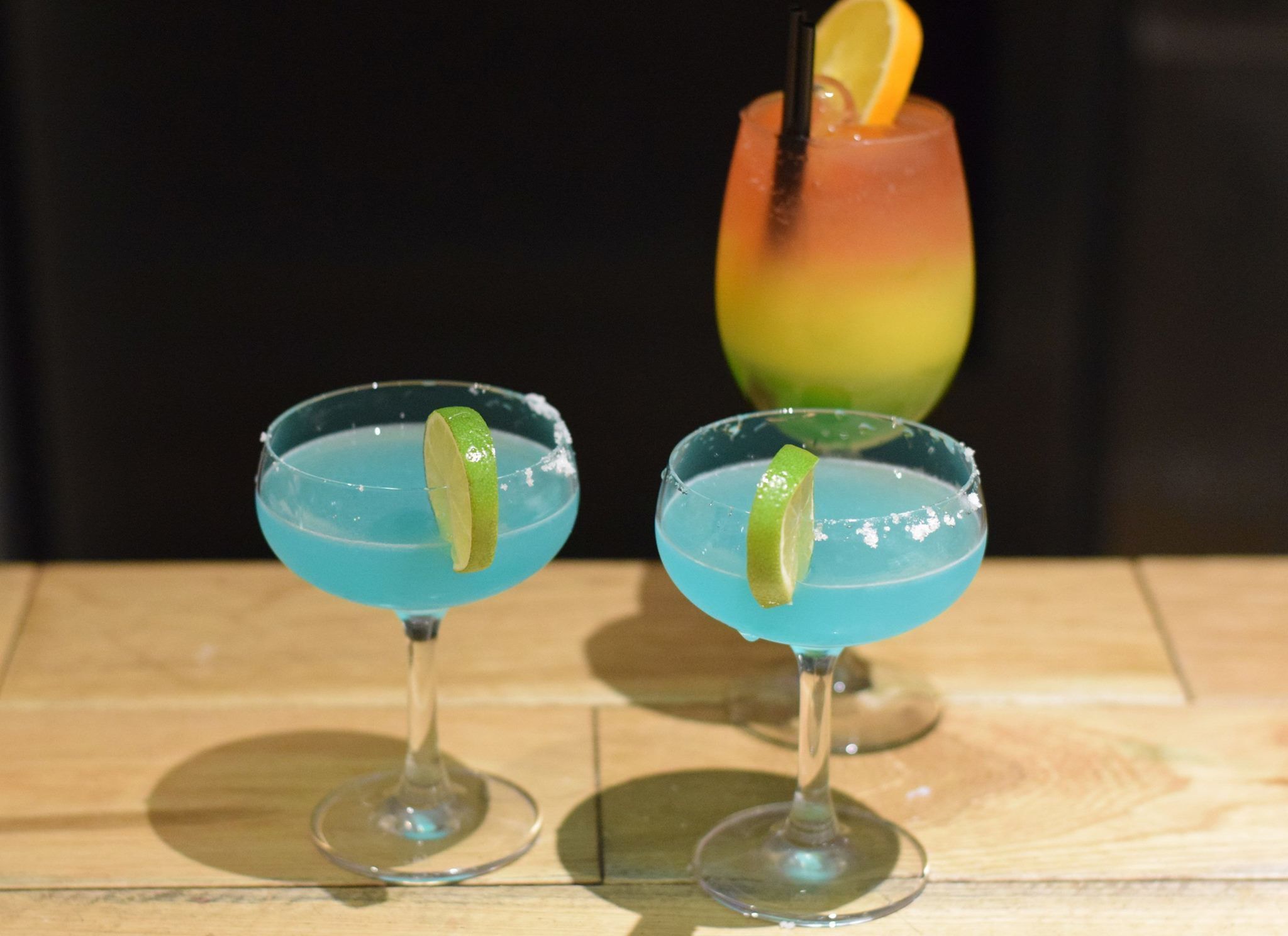 Dois cocktails com rodela de limão sobre uma superfície de madeira.