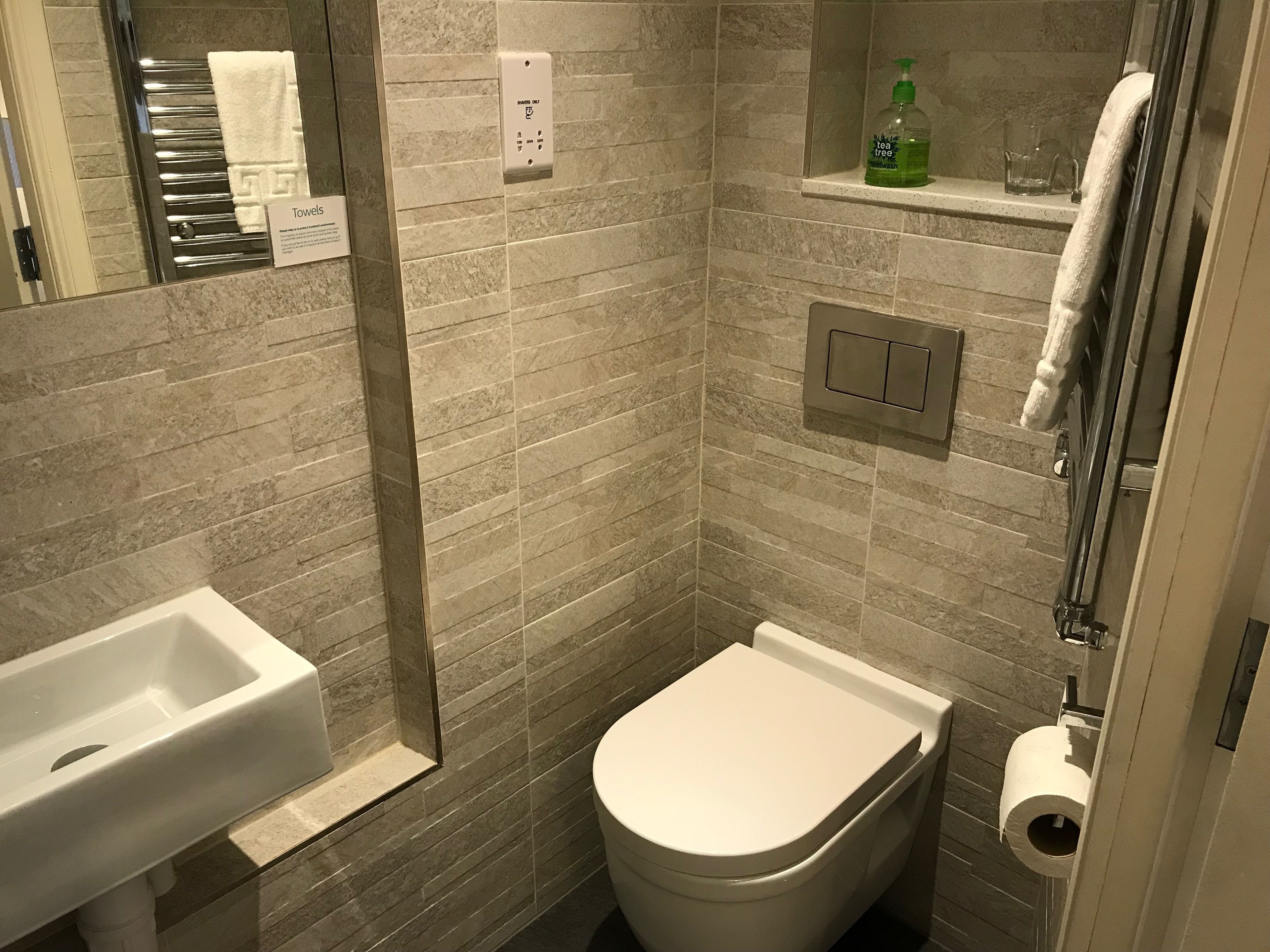 Casa de banho com sanita, lavatório, porta-toalhas e um armário com um frasco de sabonete líquido.