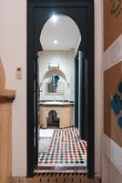 Um corredor com piso ladrilhado que leva a um quarto com pia e espelho.