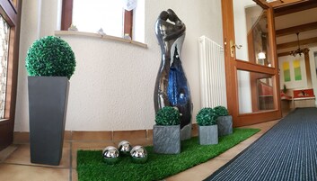 Decoração moderna com uma escultura, plantas em vasos e piso de azulejos.