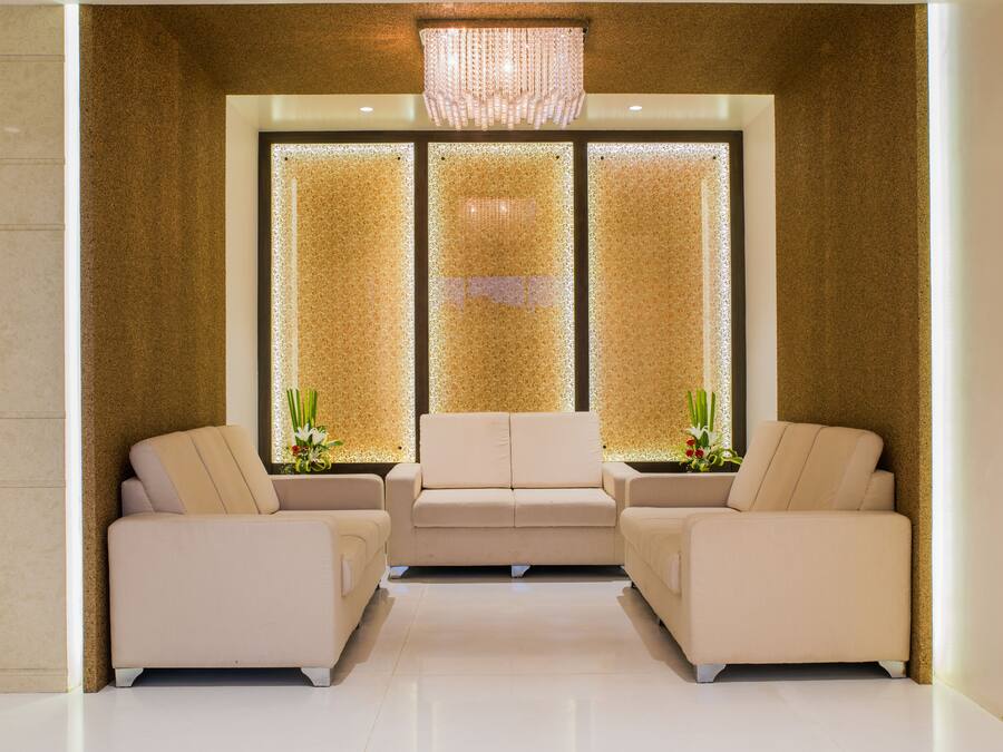 Uma área de recepção com design moderno, apresentando uma grande janela com painéis decorativos, um lustre e dois sofás dispostos para acomodação.