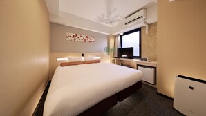 Quarto de hotel com uma cama grande, uma escrivaninha com televisão e um aparelho de ar condicionado.