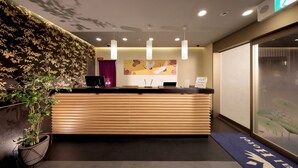 Bancada de recepção com design moderno, planta suspensa na parede e uma obra de arte emoldurada acima.