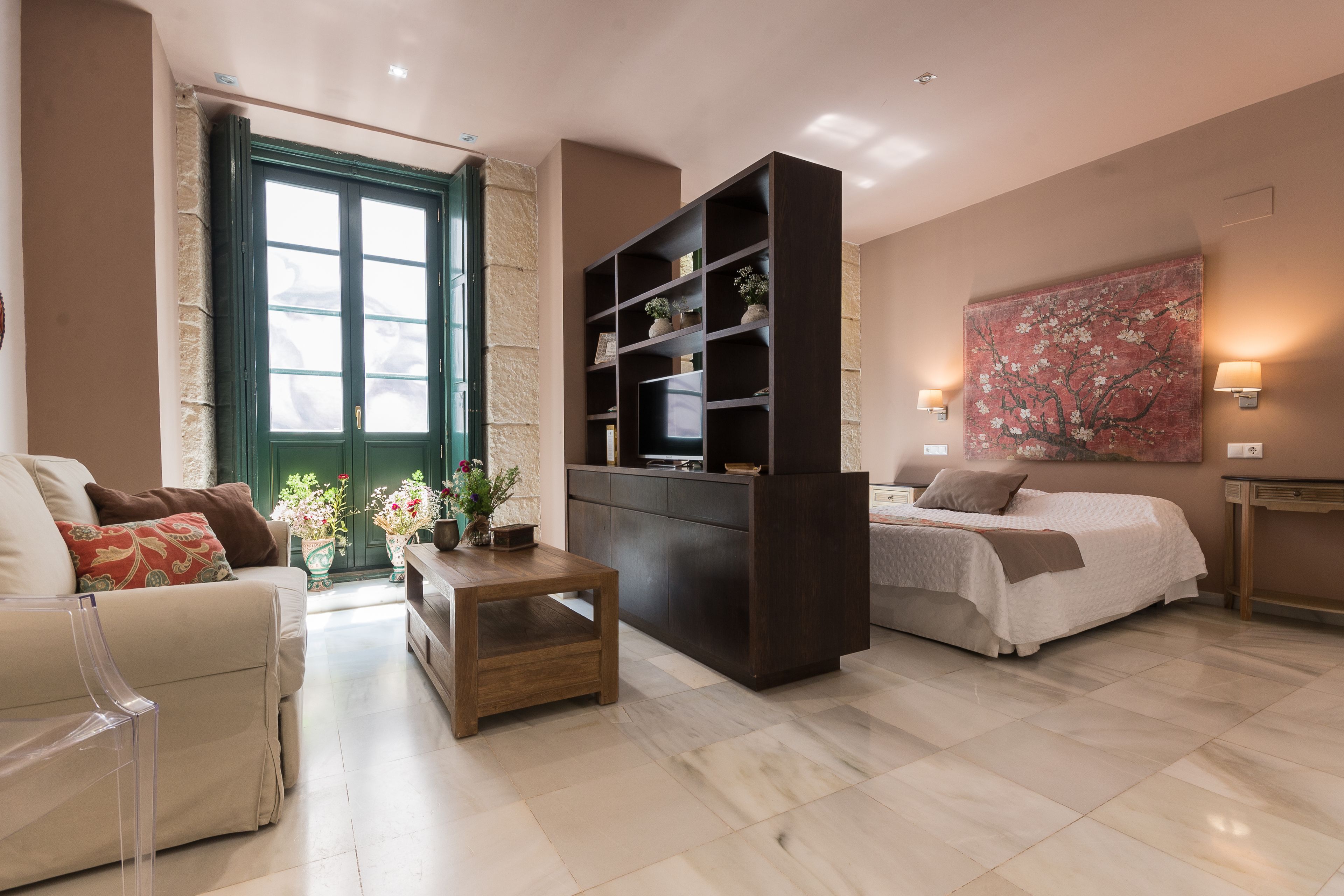 Uma sala de estar moderna com sofá, mesa de centro, rack para TV e uma cama.
