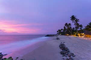 Na praia, areia branca, espreguiçadeiras, guarda-sóis