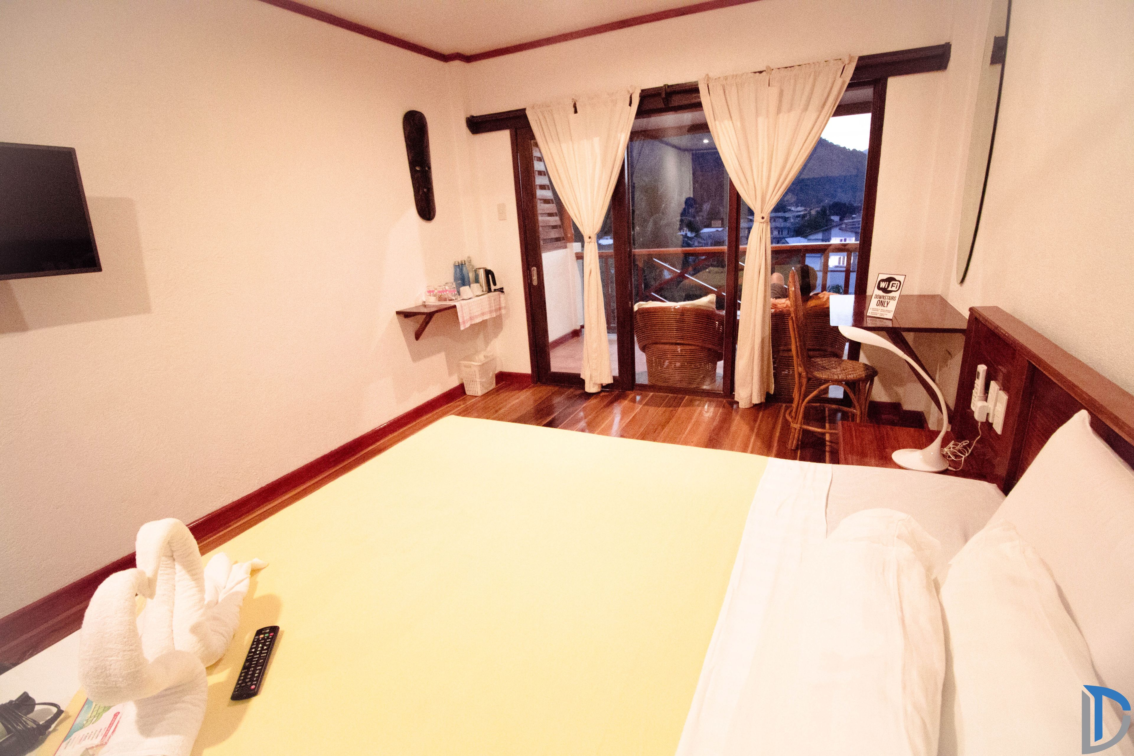 Quarto de hotel com cama, cadeira, mesa e vista para uma montanha pela janela.