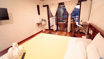 Quarto de hotel com cama, cadeira, mesa e vista para uma montanha pela janela.