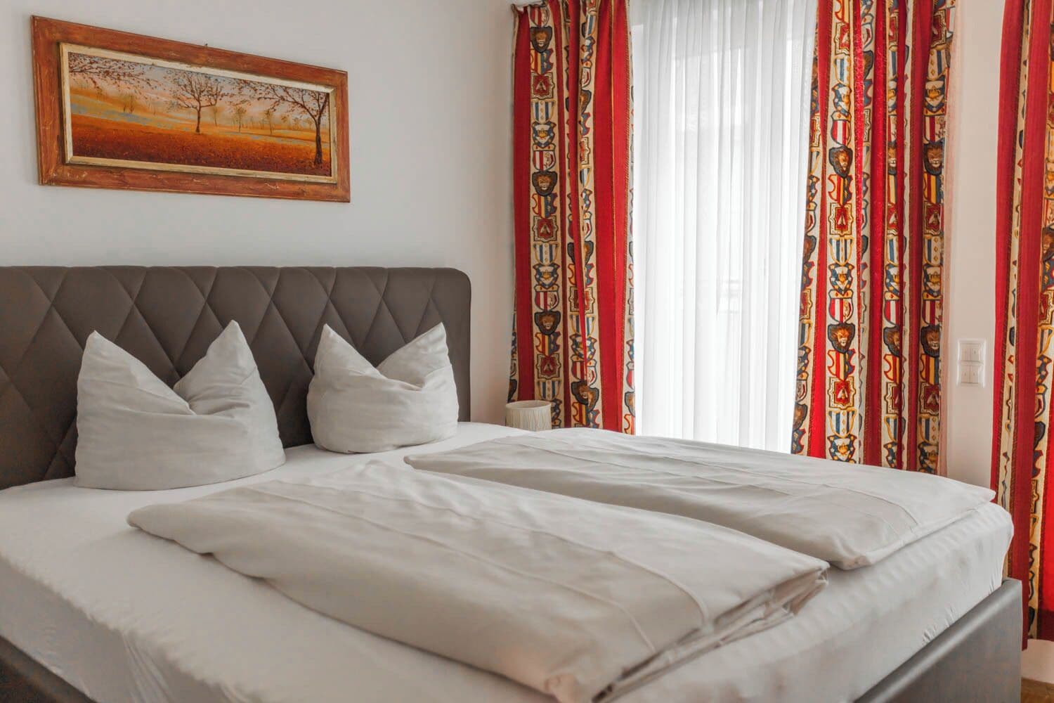 Quarto de hotel com uma cama grande, cabeceira e um quadro na parede.