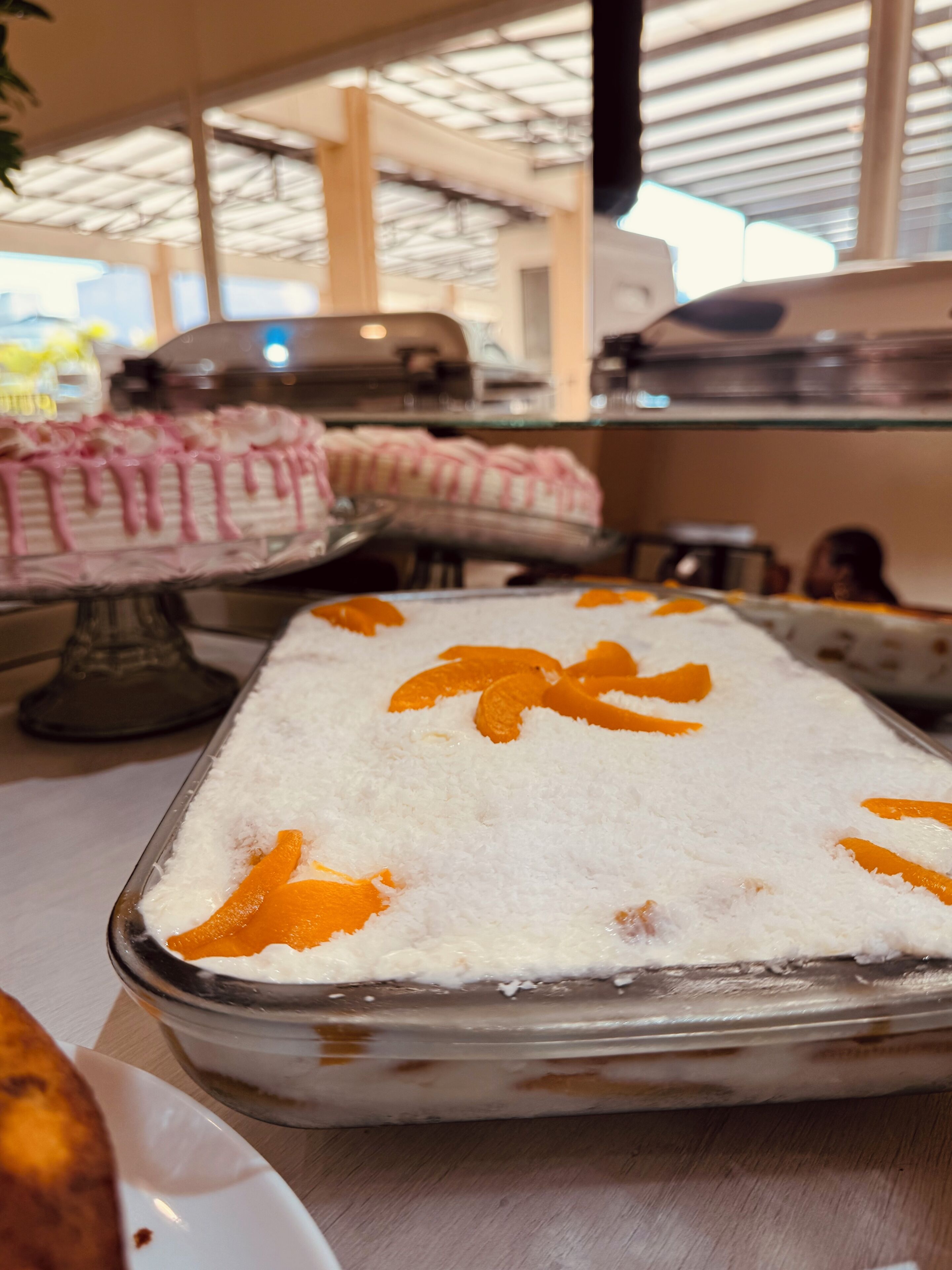 Buffet com diversos pratos, incluindo uma sobremesa com fatias de laranja por cima.