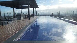 Piscina com deck de madeira e área de estar coberta.