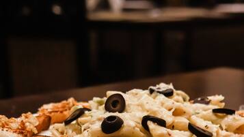 Pizza em um prato branco com um garfo ao lado, sobre um tapete de mesa trançado.