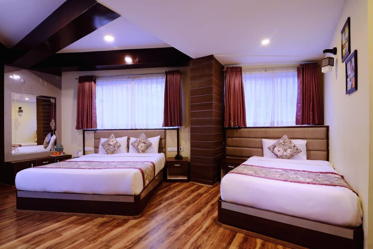 Quarto de hotel com duas camas, piso de madeira, um espelho grande e janelas com cortinas.
