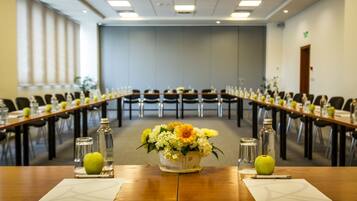 Uma sala de conferências com uma mesa comprida, cadeiras e um arranjo floral.