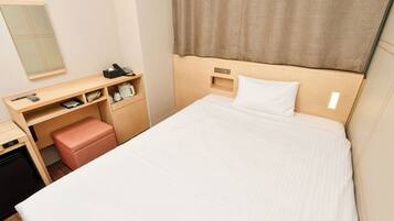 Quarto de hotel com cama, escrivaninha, cadeira, mesa pequena, espelho e cortina.