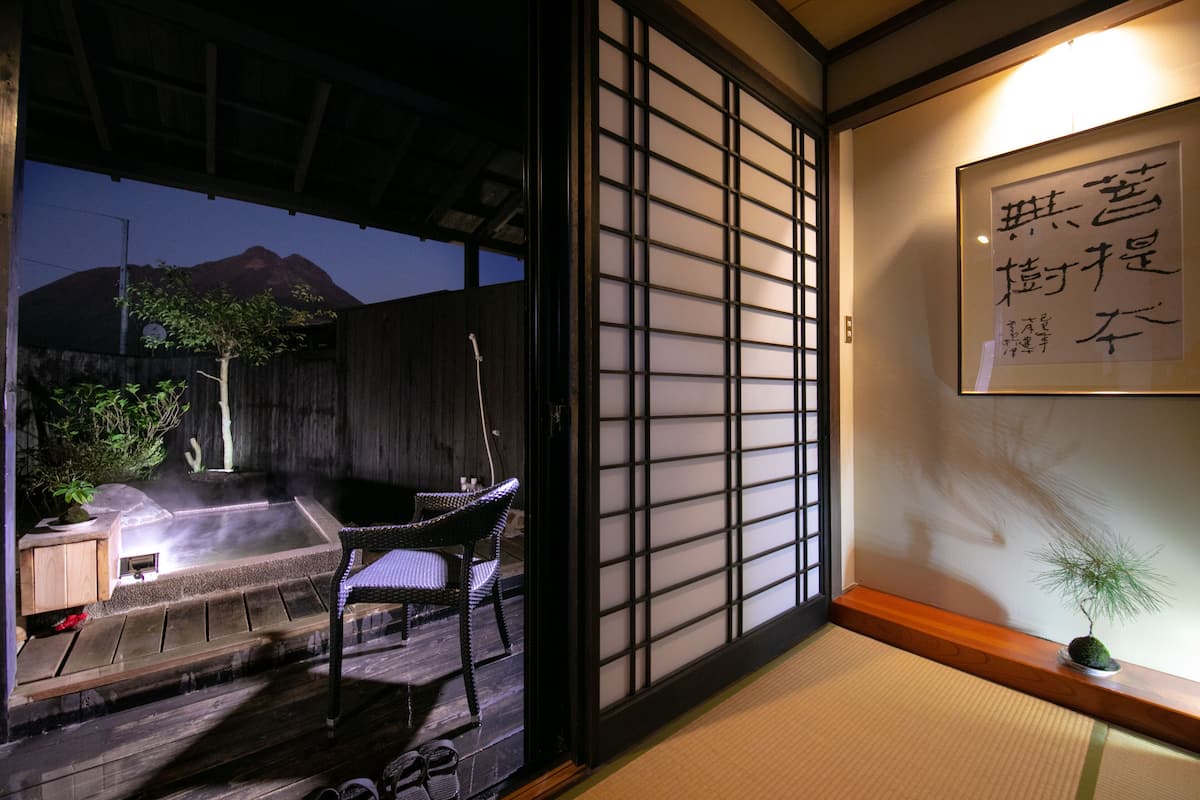 Um quarto japonês tradicional com tatames, uma mesa baixa, uma cadeira e um biombô shoji.