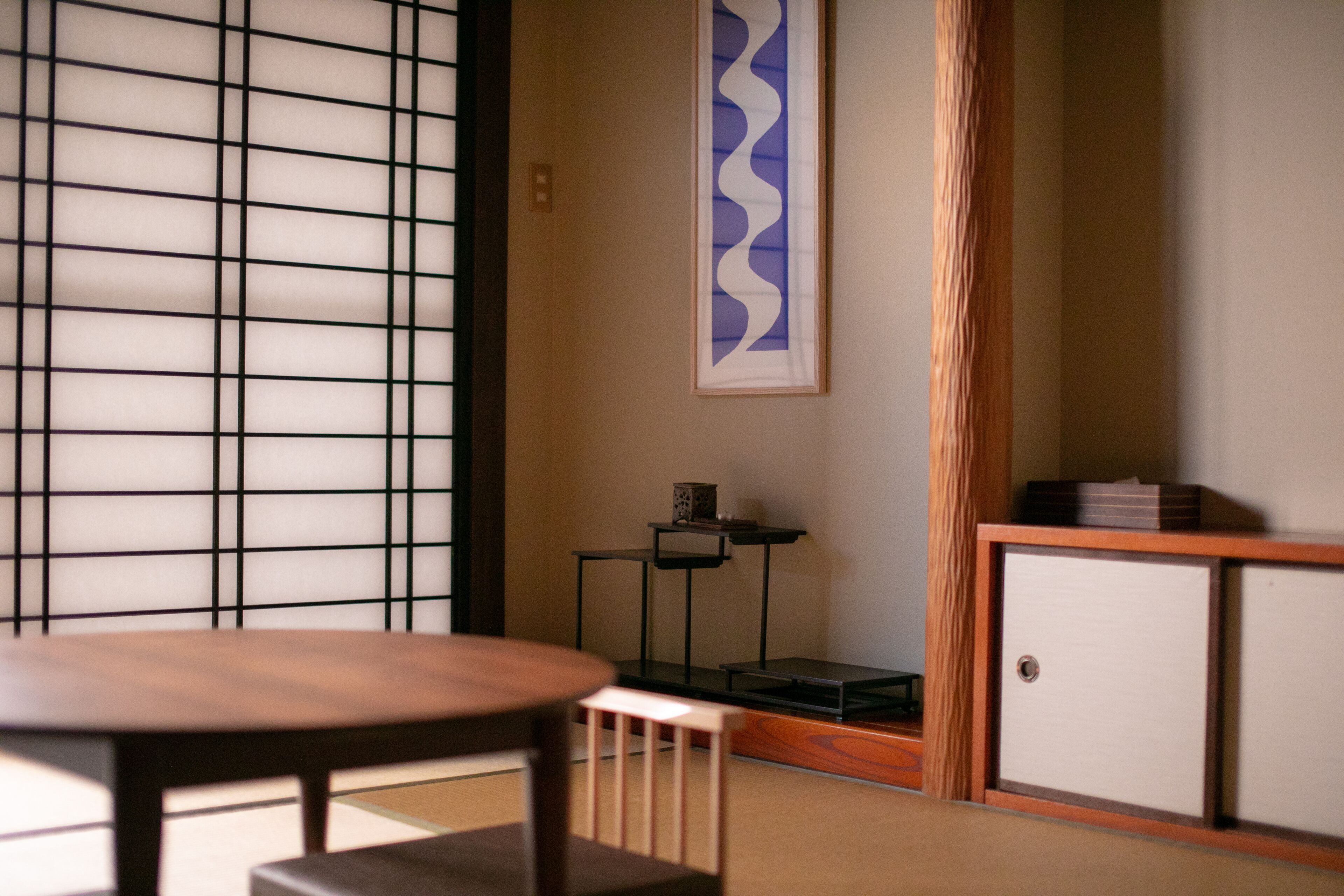 Um quarto japonês tradicional com tatames, uma mesa de madeira baixa, uma porta deslizante e um biombos shoji.